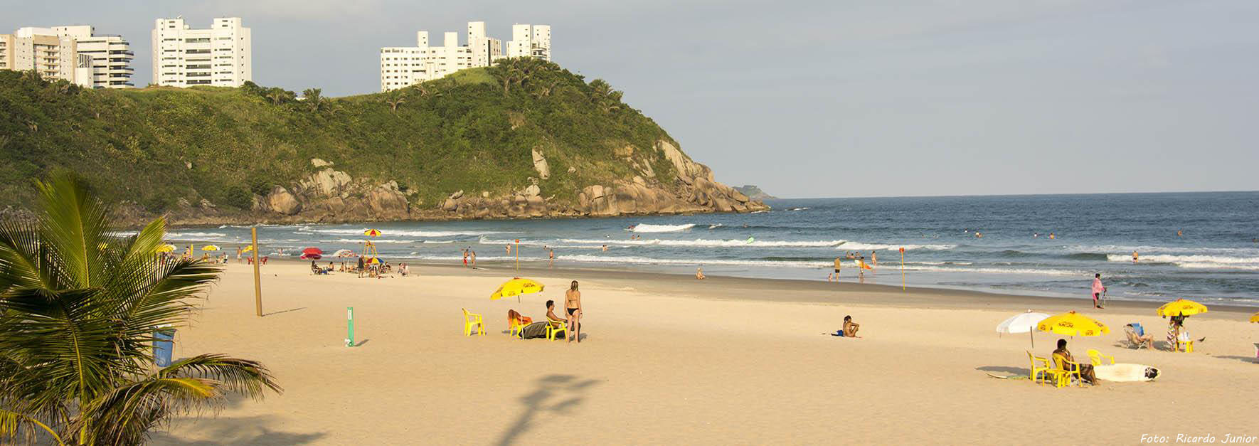 Imagem da linda Praia do Perequê com vegetação no canto da praia.